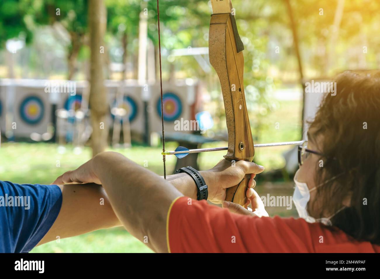 Female teacher teaches student to aim at goal. An archer teaching young ...
