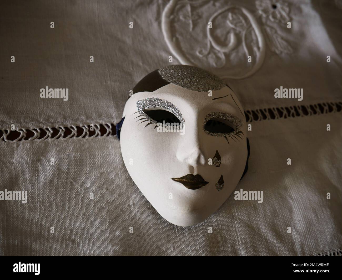 Small hand-painted Venetian mask on a table cover from the early 1900s ...