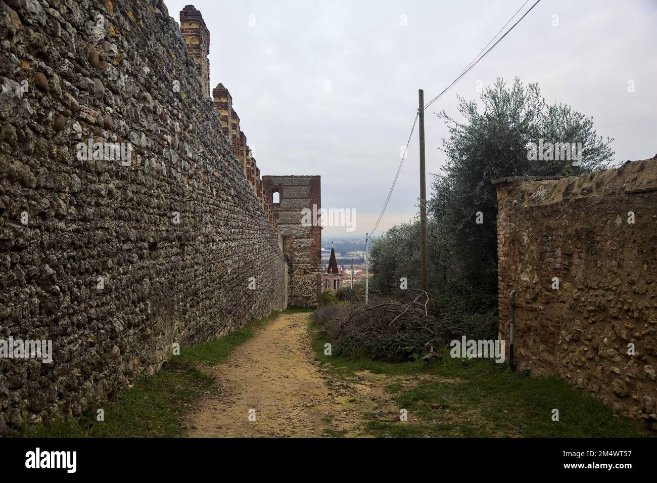Dirt path next to an ancient fortification in a park with a bell tower ...
