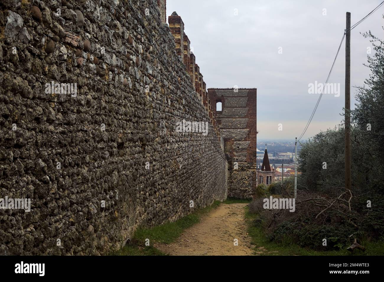 Dirt path next to an ancient fortification in a park with a bell tower ...