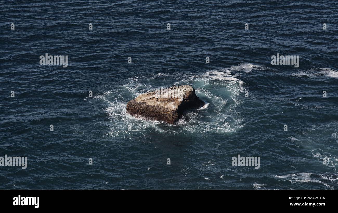 A single rock in the ocean water Stock Photo - Alamy