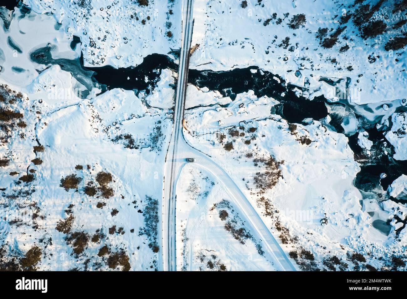 Aerial view of a car driving through the snowy winter landscape with a ...