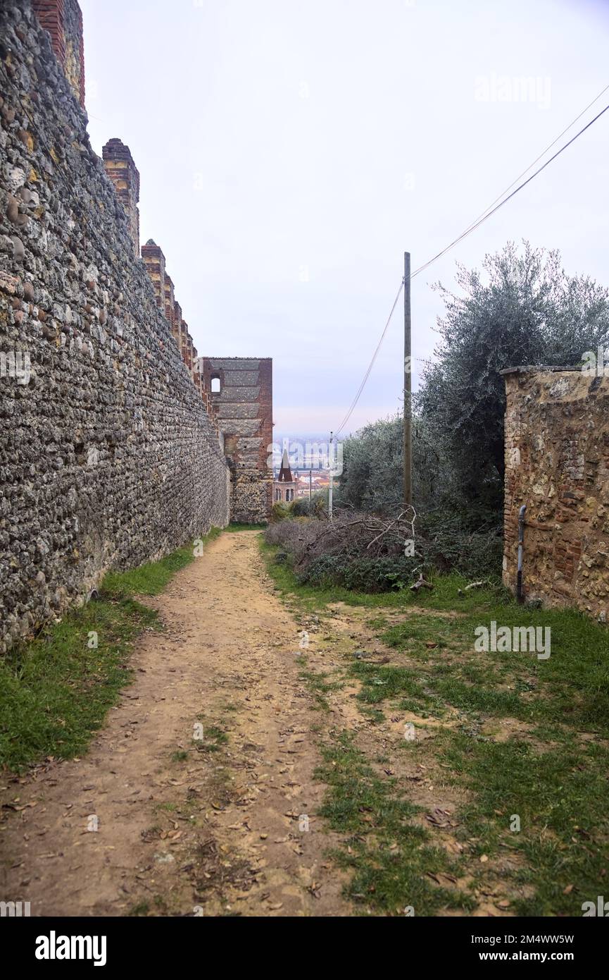 Dirt path next to an ancient fortification in a park with a bell tower ...