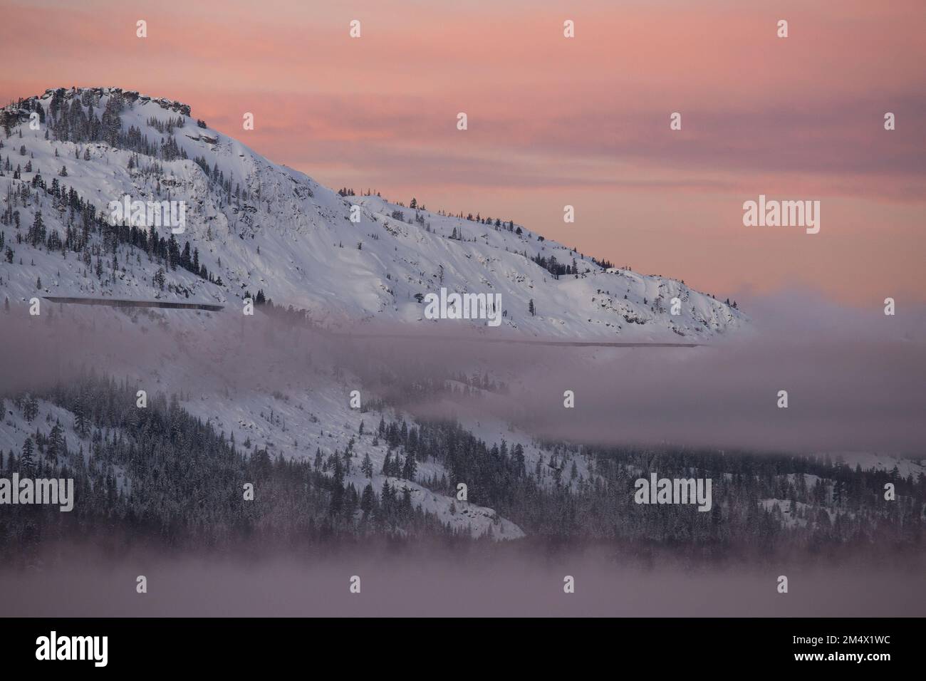 Morning alpine glow lights up the top of Donner Pass on a winter ...