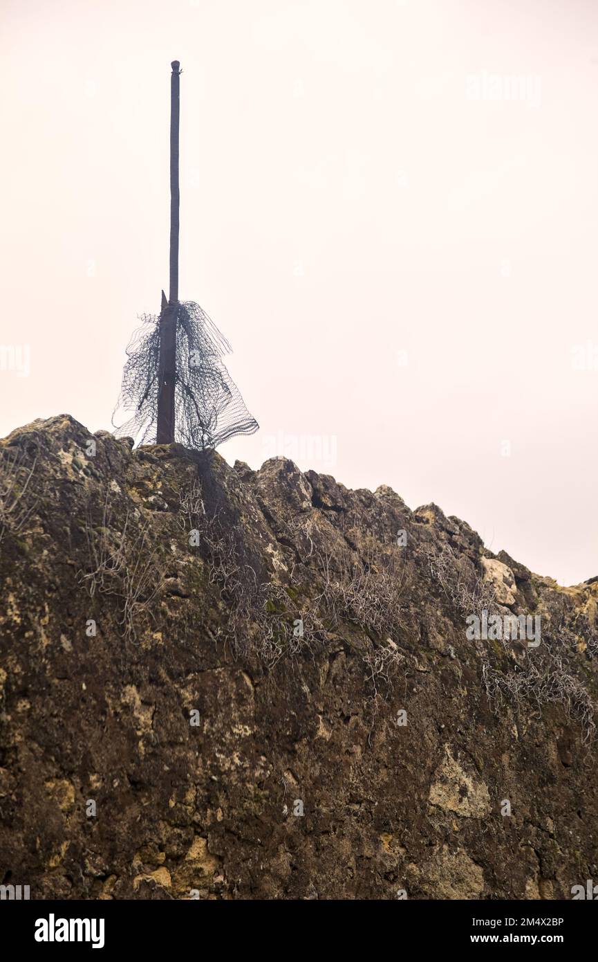 Net stuck in a metallic pole on the top of a stone wall with a cloudy ...