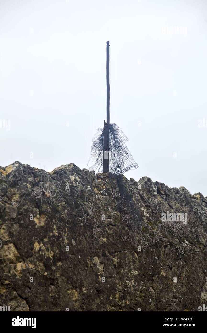 Net stuck in a metallic pole on the top of a stone wall with a cloudy ...