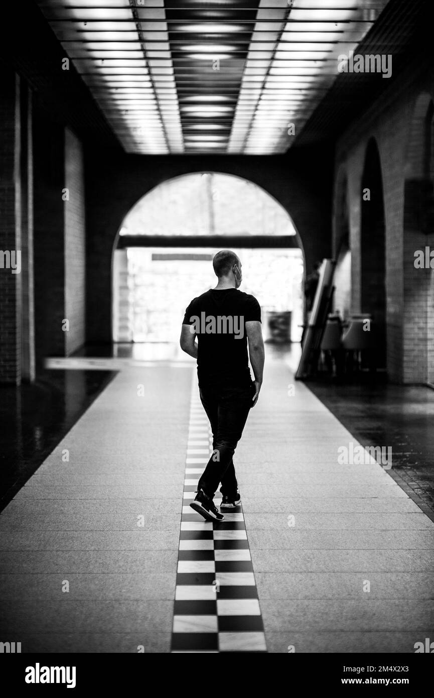 A black-and-white vertical shot of a young guy walking inside a ...