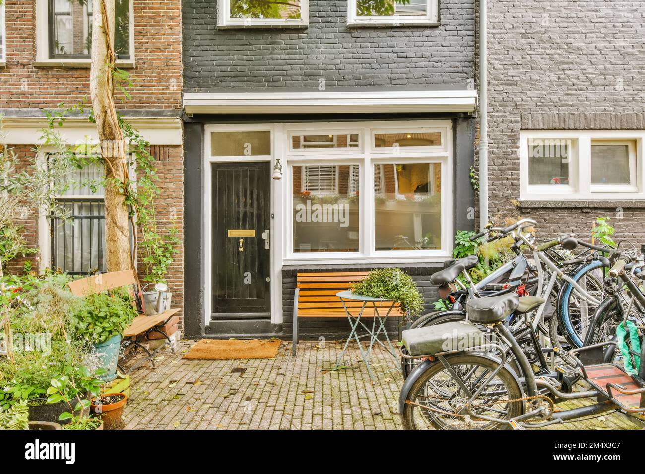 two bikes parked in front of a house on a cobbed street with potted ...