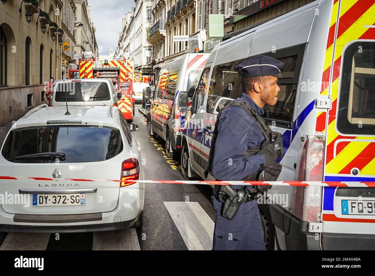 A policeman walks past some ambulance trucks in the scene. French ...