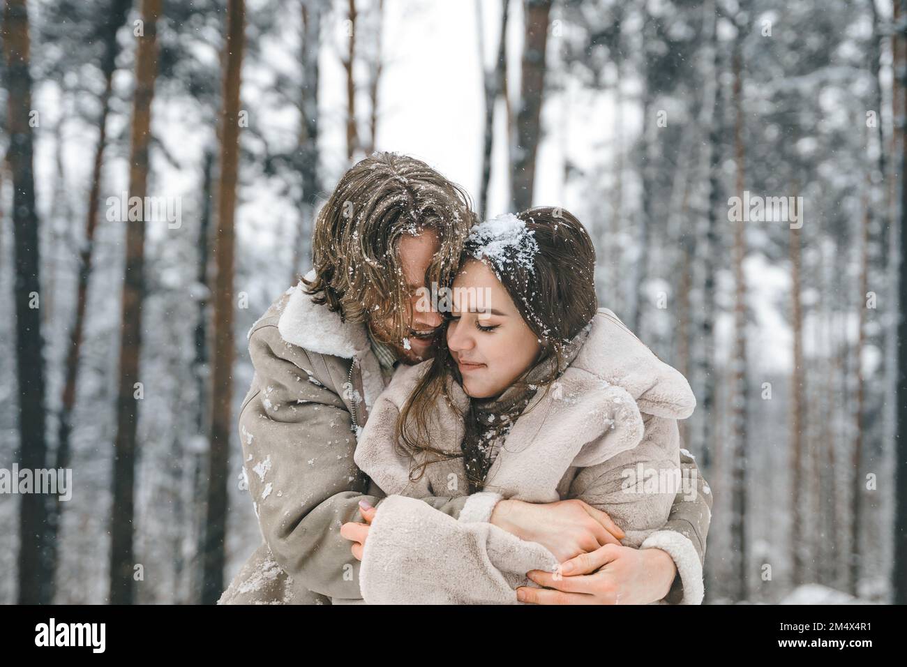 Love romantic young couple. Guy hugging kissing girl in snowy winter forest. Walking,having fun ...