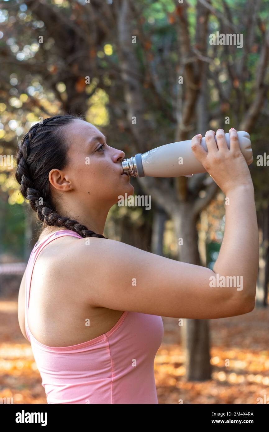 A vertical shot of a woman having a break while drinking water during ...
