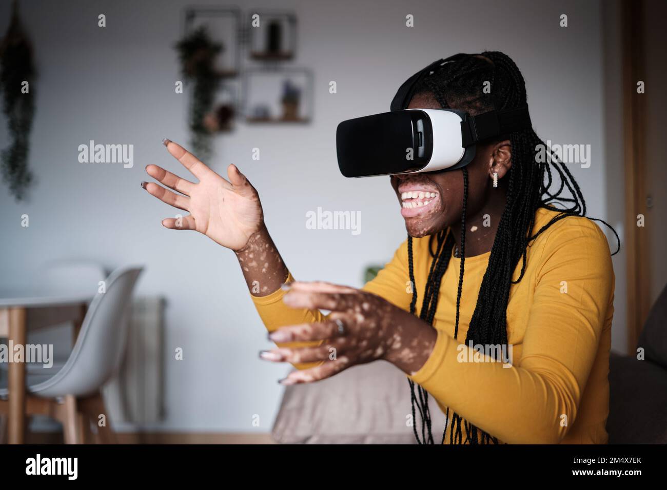 Cheerful black woman with vitiligo skin playing videogame in VR Stock ...
