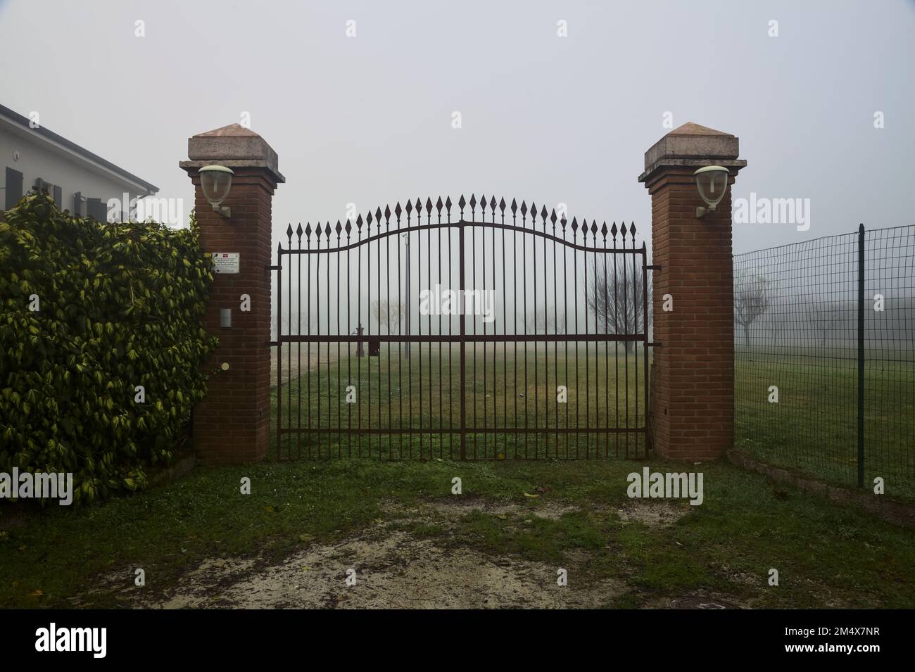 Gate in front of an empty lawn on a foggy day Stock Photo - Alamy