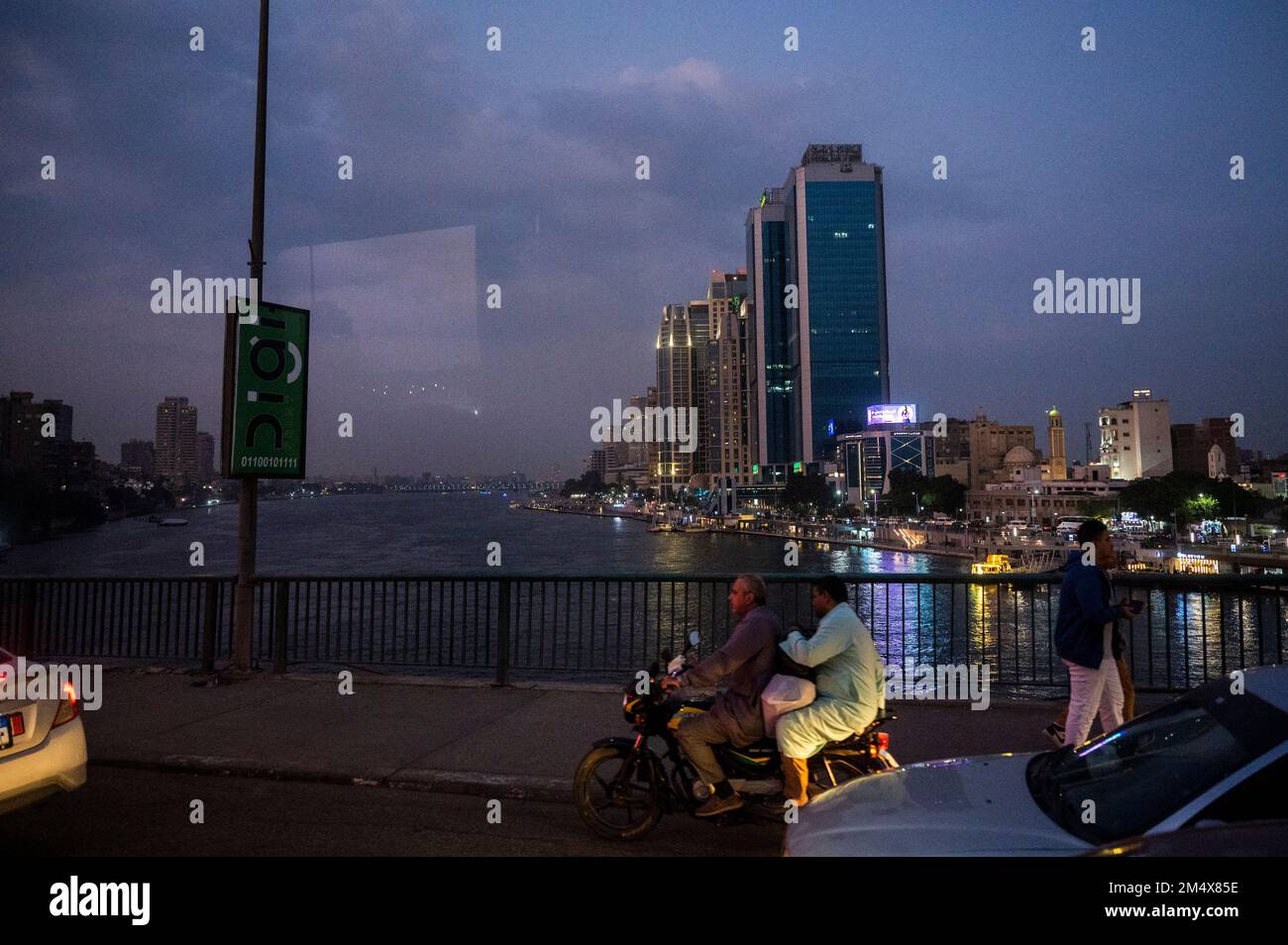 Kairo, Egypt. 12th Nov, 2022. Two people ride a scooter across a bridge ...