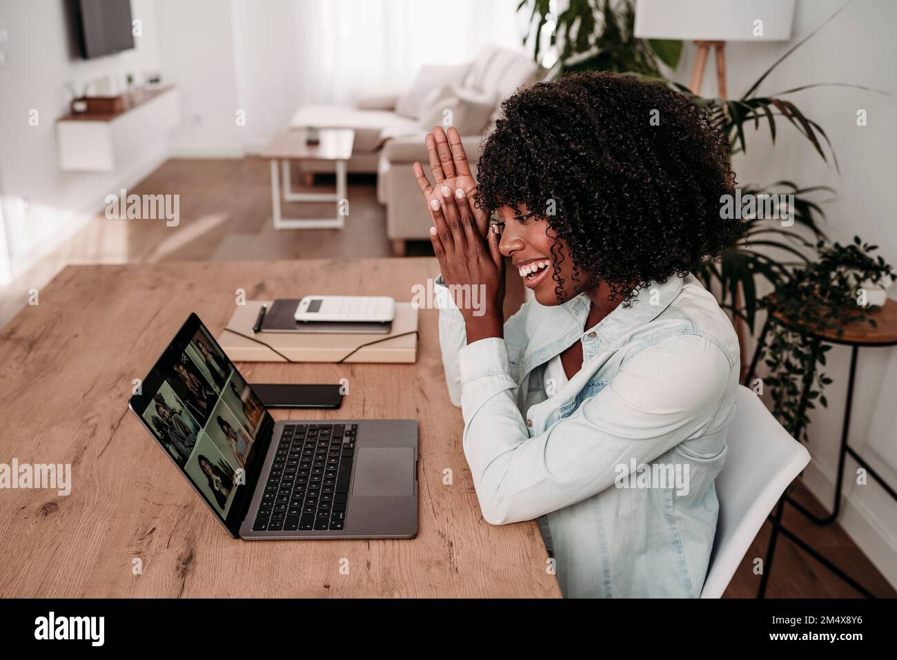 Businesswoman clapping hands on video call through laptop at home Stock ...