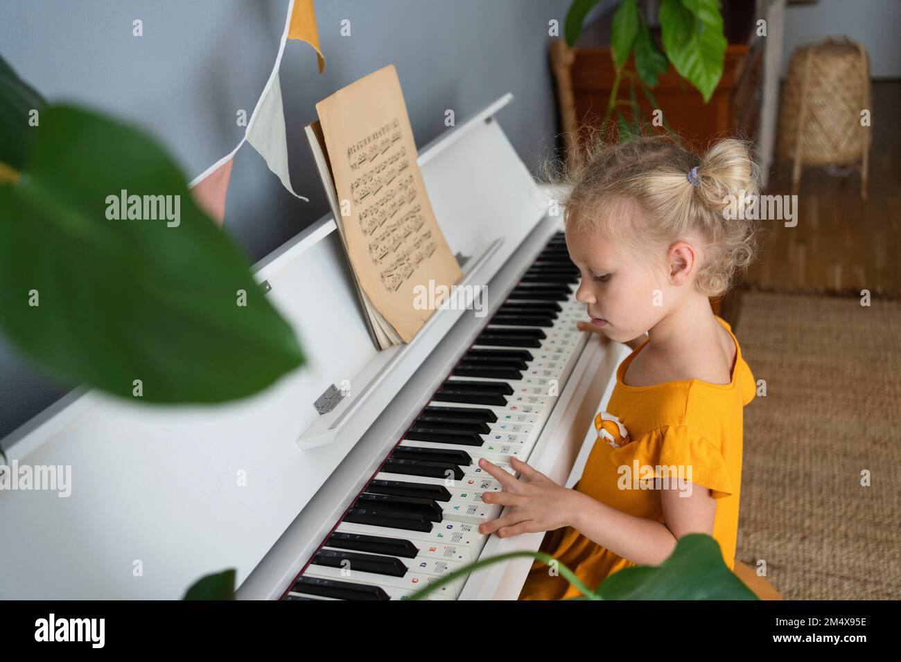 Blond girl practicing piano at home Stock Photo - Alamy