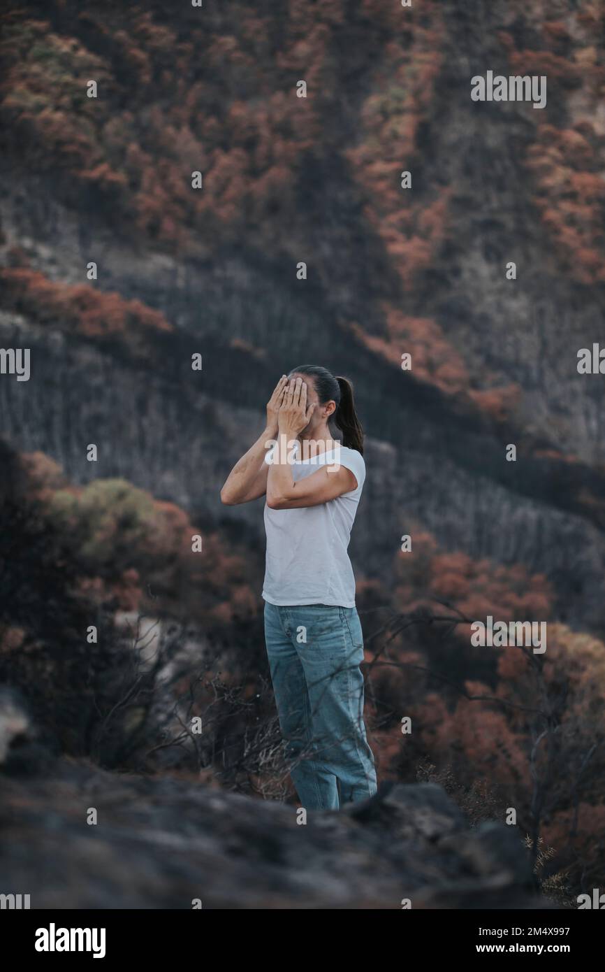Desperate woman covering face standing in forest Stock Photo - Alamy