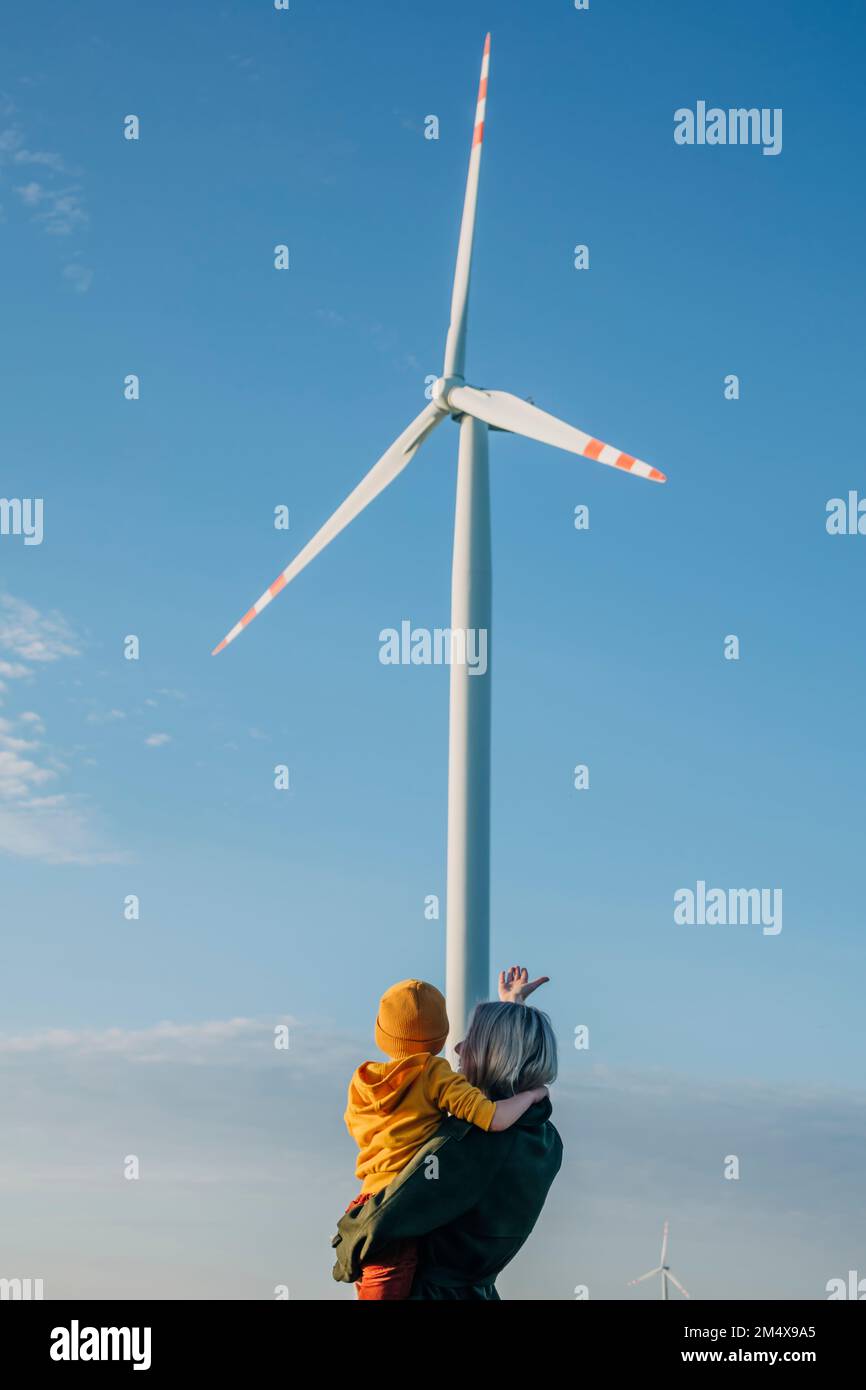 Mother showing wind turbine to son in front of sky Stock Photo - Alamy