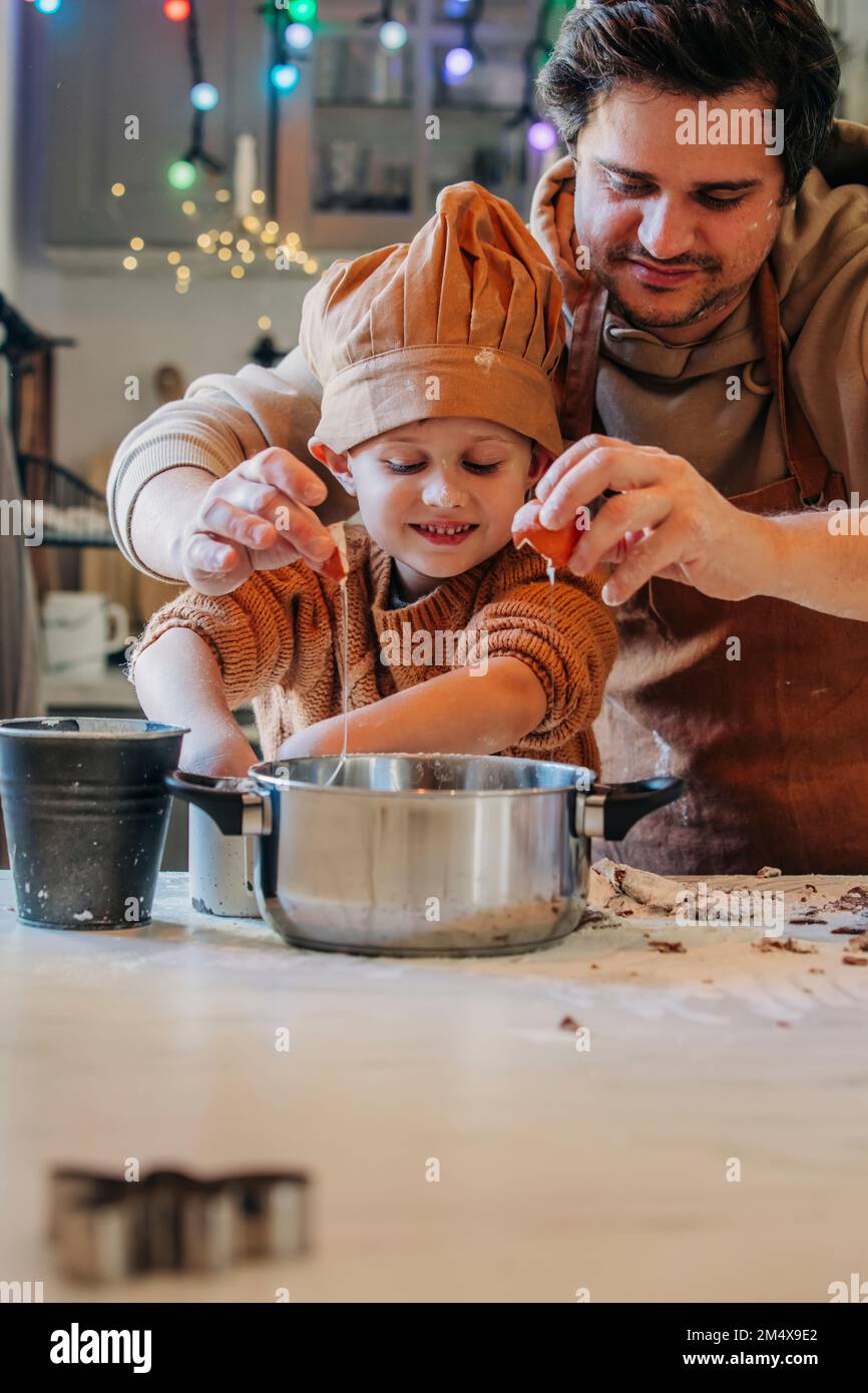 Smiling son with father cracking egg in utensil at home Stock Photo - Alamy