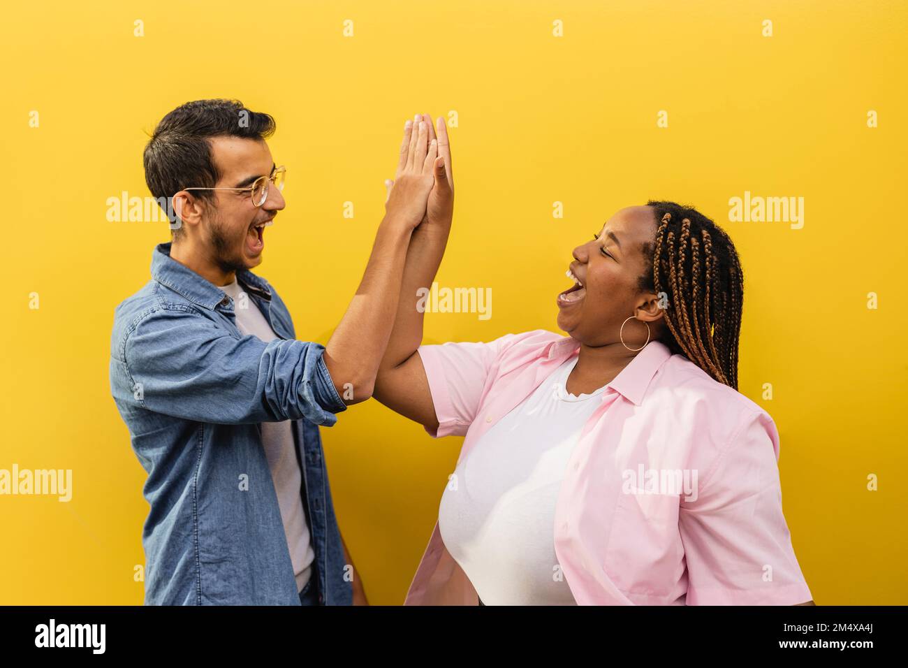 Cheerful man and woman giving high-five to each other in front of ...
