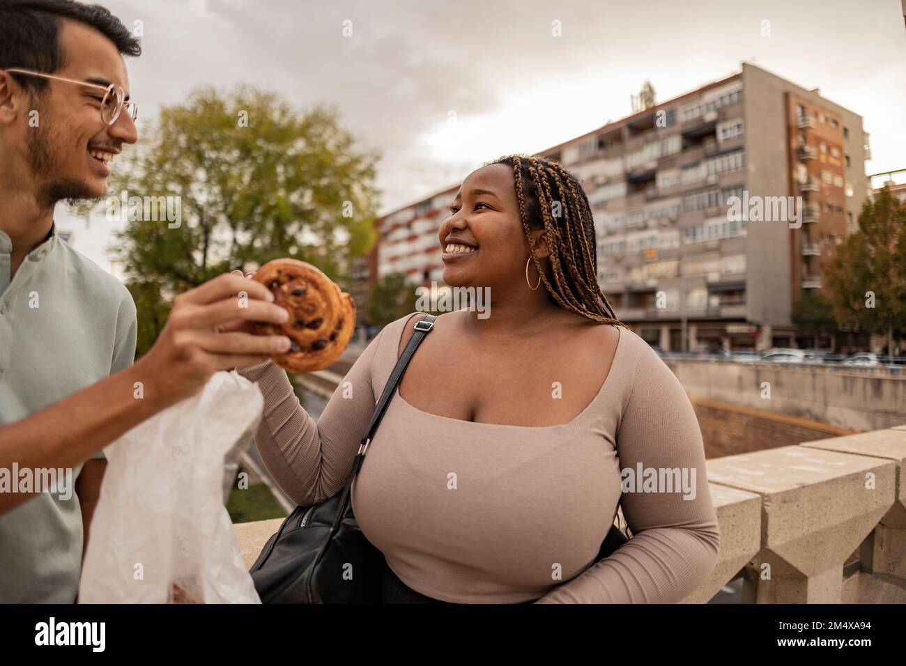 Smiling young couple with snacks standing in front of building Stock ...