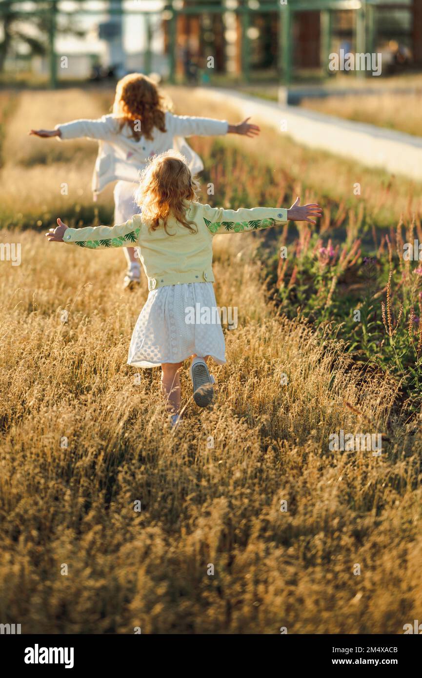 Happy girls with arms outstretched walking on grass Stock Photo - Alamy