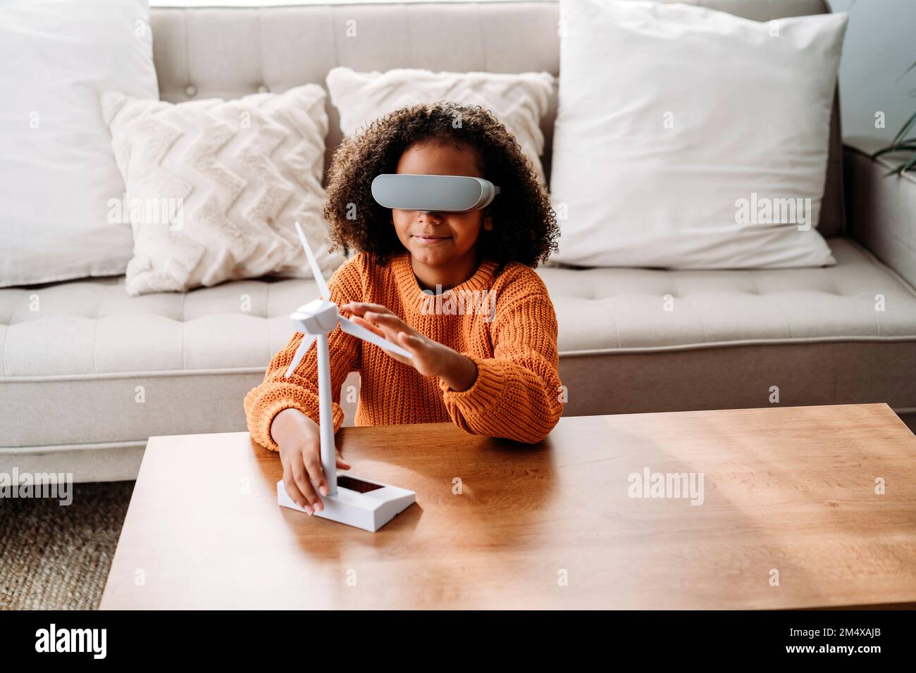 Girl with virtual reality simulator sitting with wind turbine model in ...