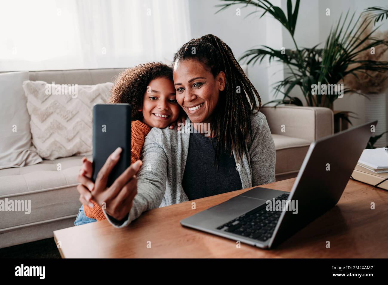 Happy mother and daughter talking on video call through smart phone at ...