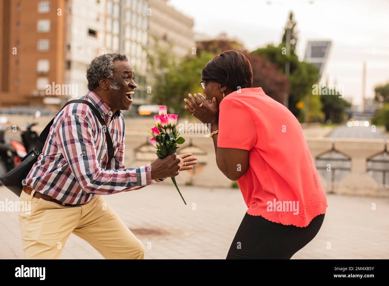 Cheerful man giving bunch of flowers to excited woman Stock Photo - Alamy