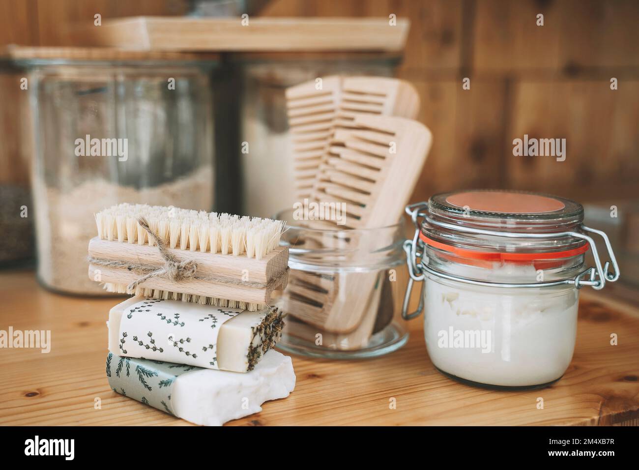 Stack of soap bars and scrubbing brush with hair combs and jar on table ...