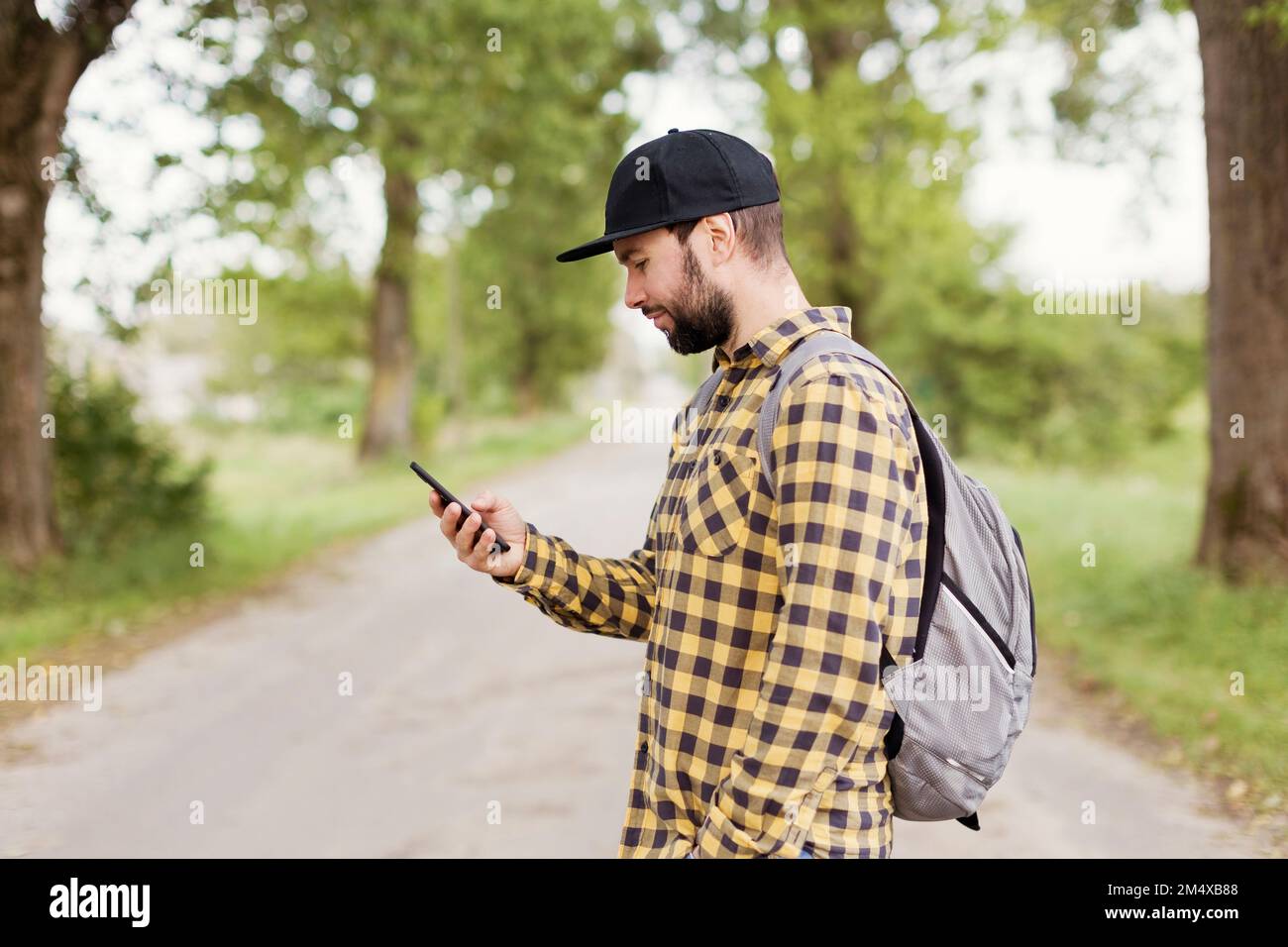 Man wearing cap using smart phone on road Stock Photo - Alamy