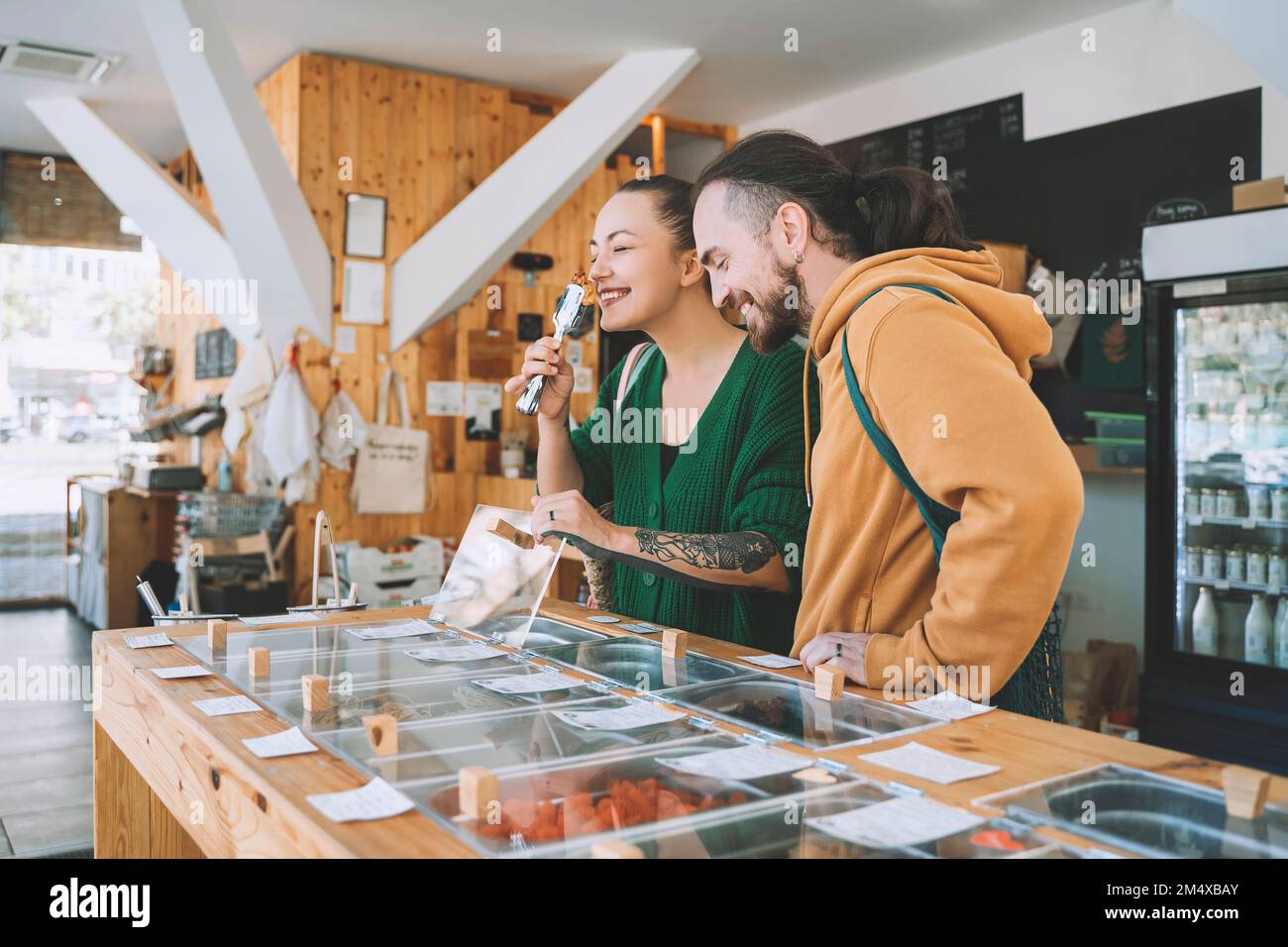 Smiling woman smelling food by man in convenience store Stock Photo - Alamy