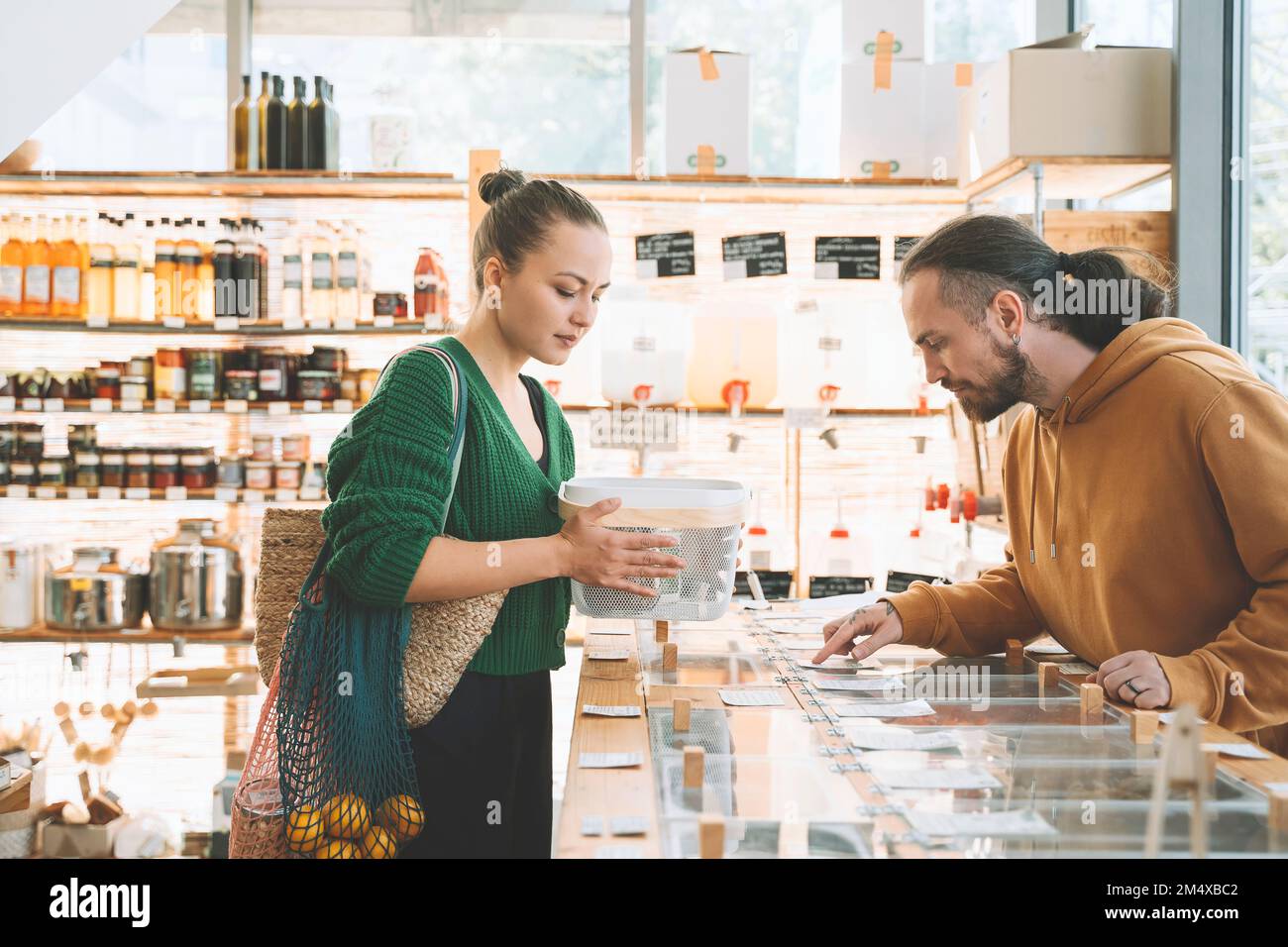Man reading labels on counter by woman with container in shop Stock ...