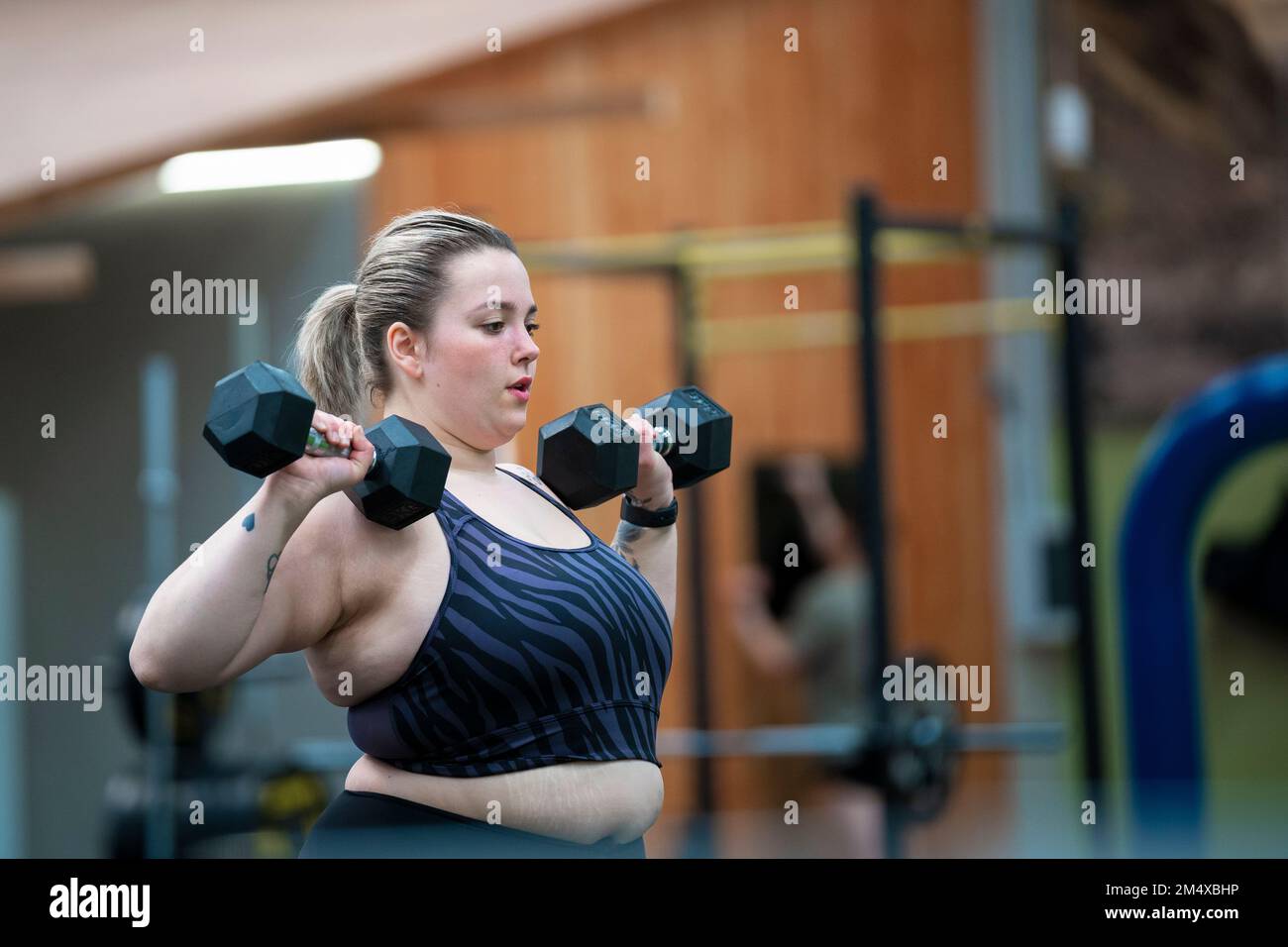 Overweight woman doing exercise with dumbbells in gym Stock Photo - Alamy