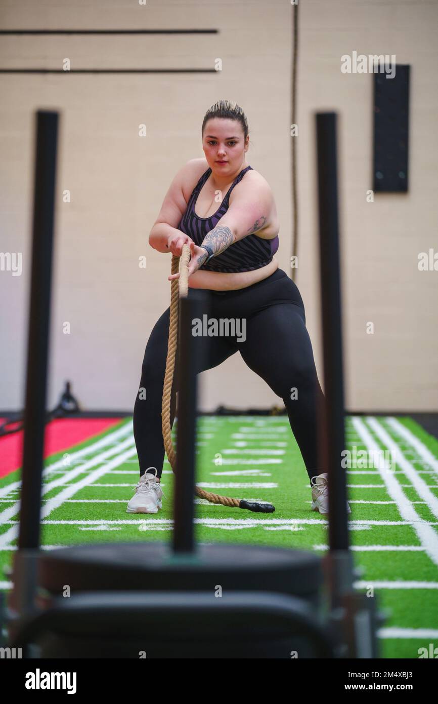 Overweight woman pulling weights with rope in gym Stock Photo - Alamy
