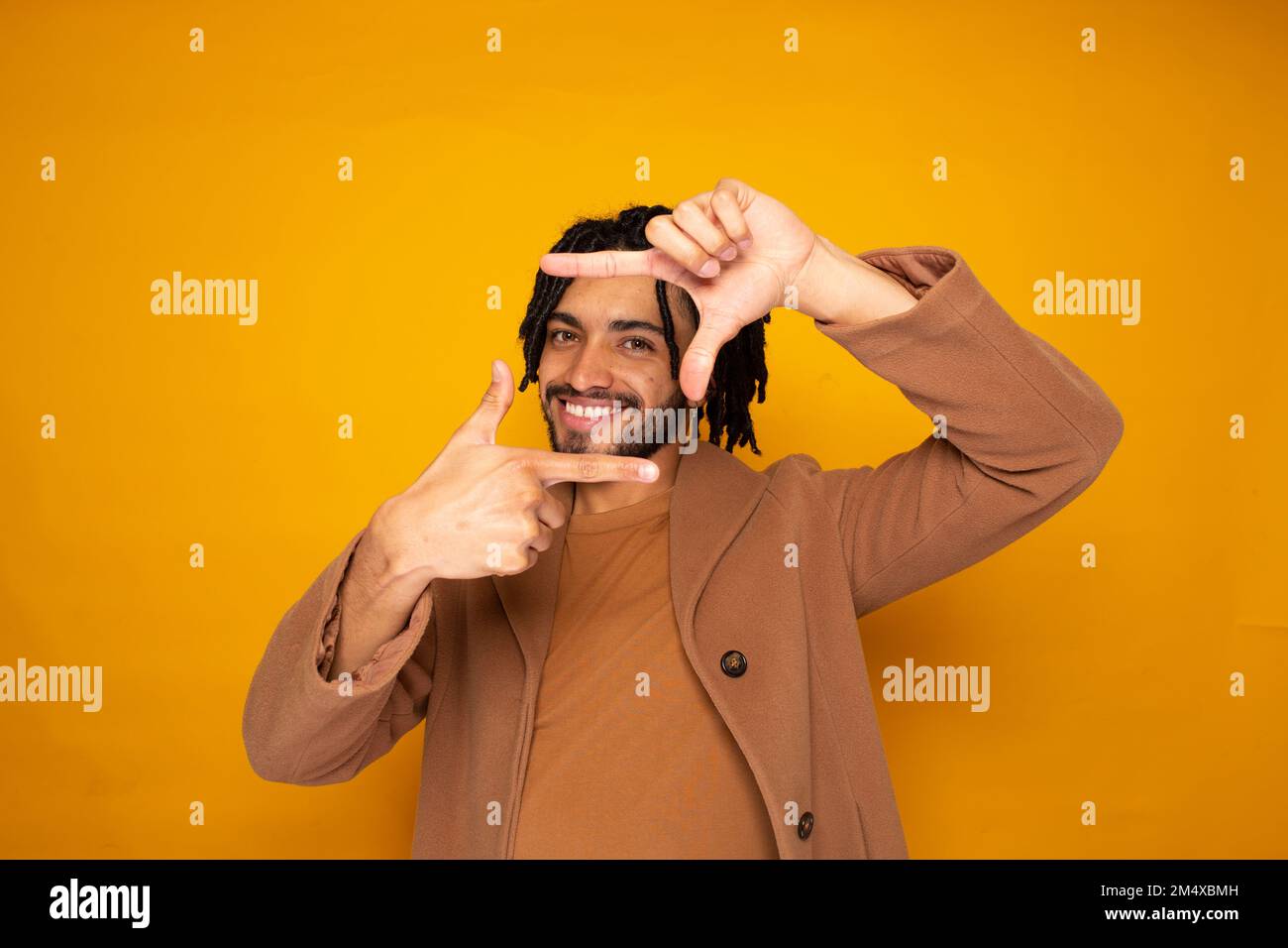 Smiling man making finger frame against yellow background Stock Photo ...