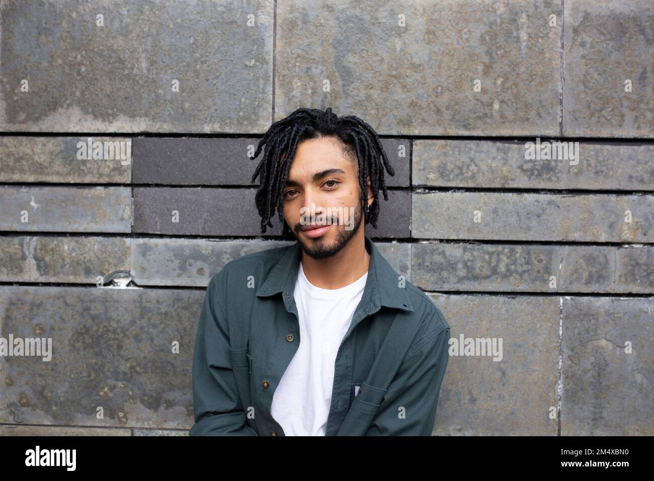 Young man with dreads in front of wall Stock Photo - Alamy