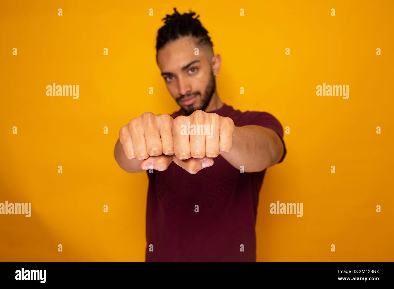 Confident man showing fists against yellow background Stock Photo - Alamy