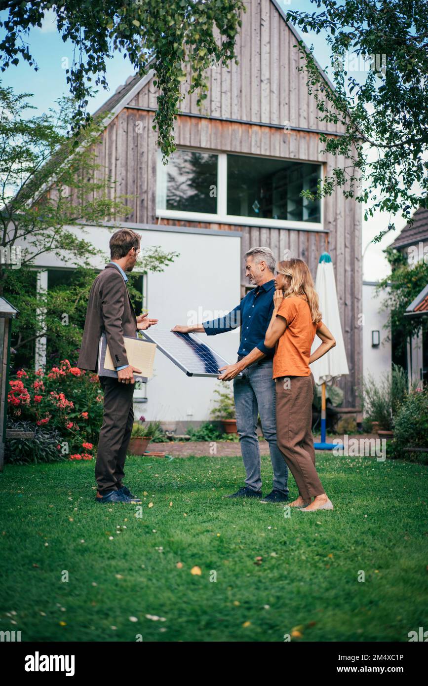 Real estate agent having discussion over solar panel with customers in ...