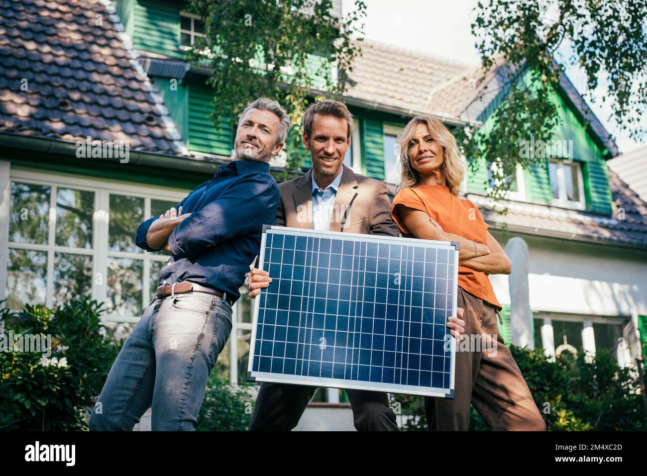 Confident man and woman with real estate agent charging solar panel ...