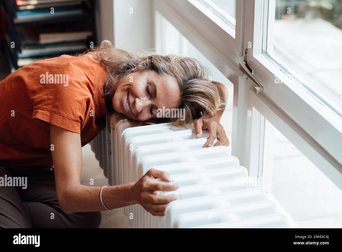 Happy mature woman leaning on radiator at home Stock Photo - Alamy