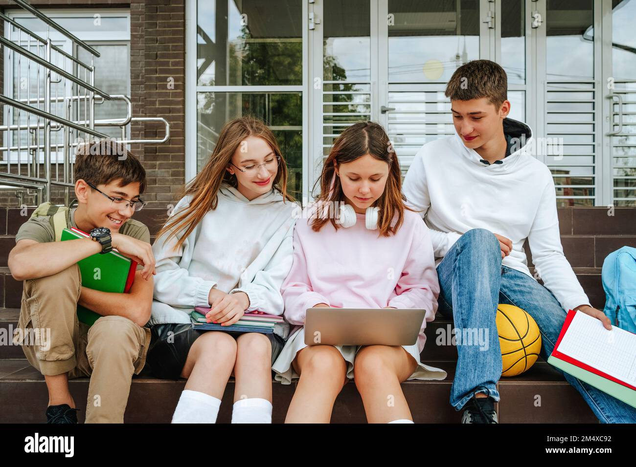 Pupils doing homework using laptop sitting on steps Stock Photo - Alamy