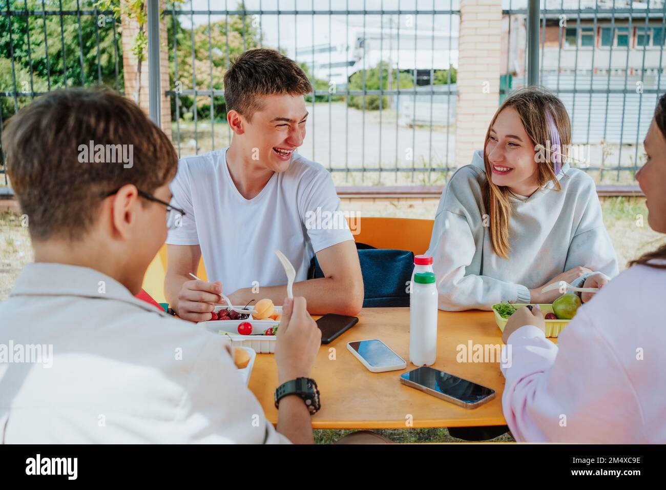 Happy teenage friends having lunch sitting at table in schoolyard Stock ...