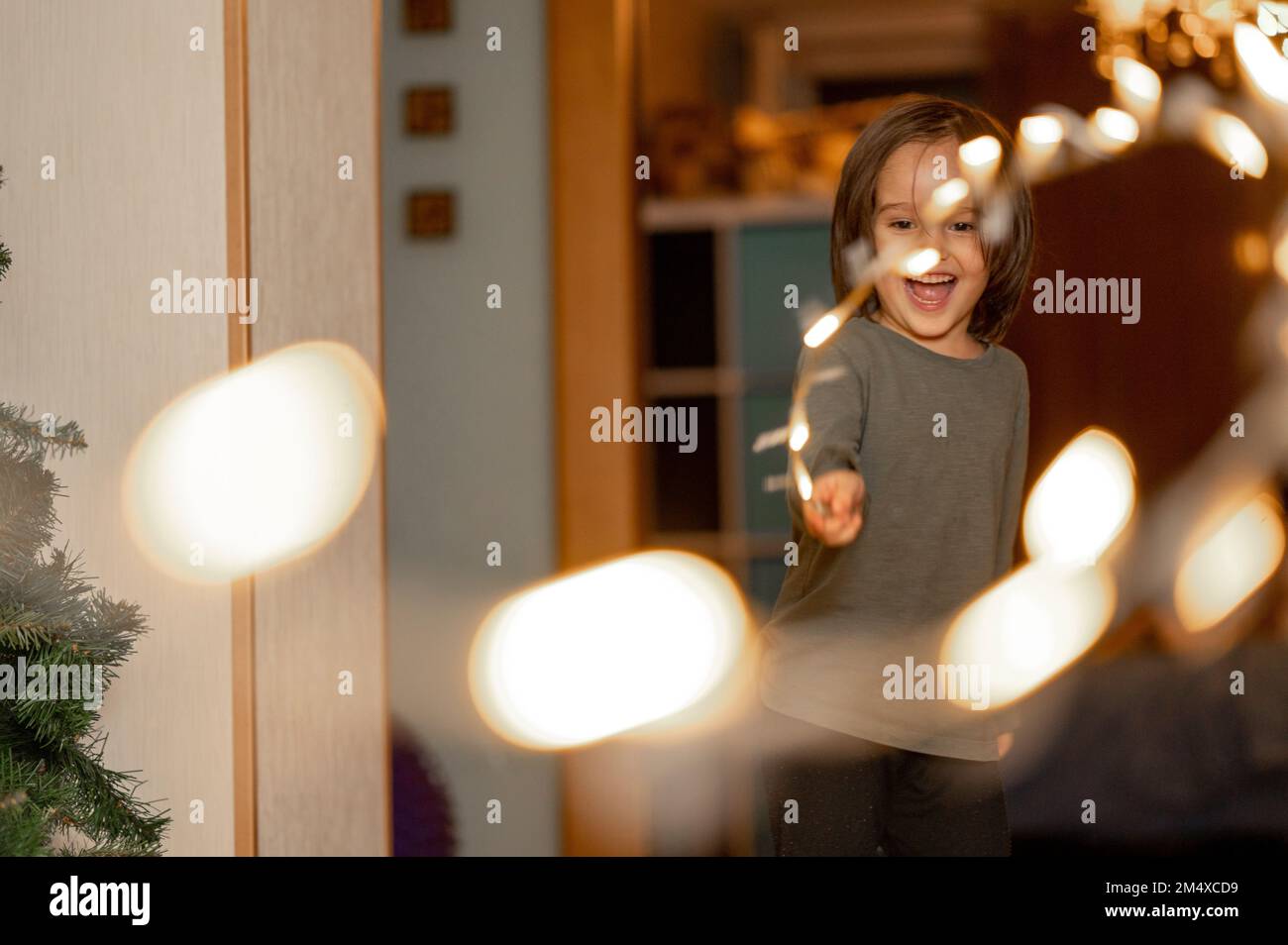 Happy cute boy playing with string light at home Stock Photo - Alamy