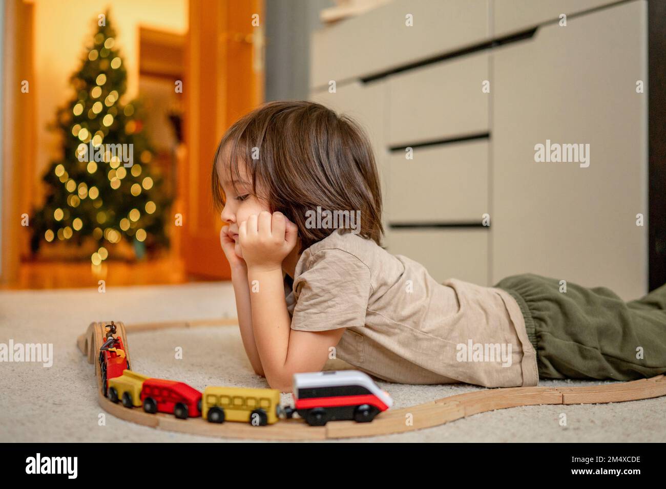 Thoughtful boy looking at wooden toy train lying on floor Stock Photo ...