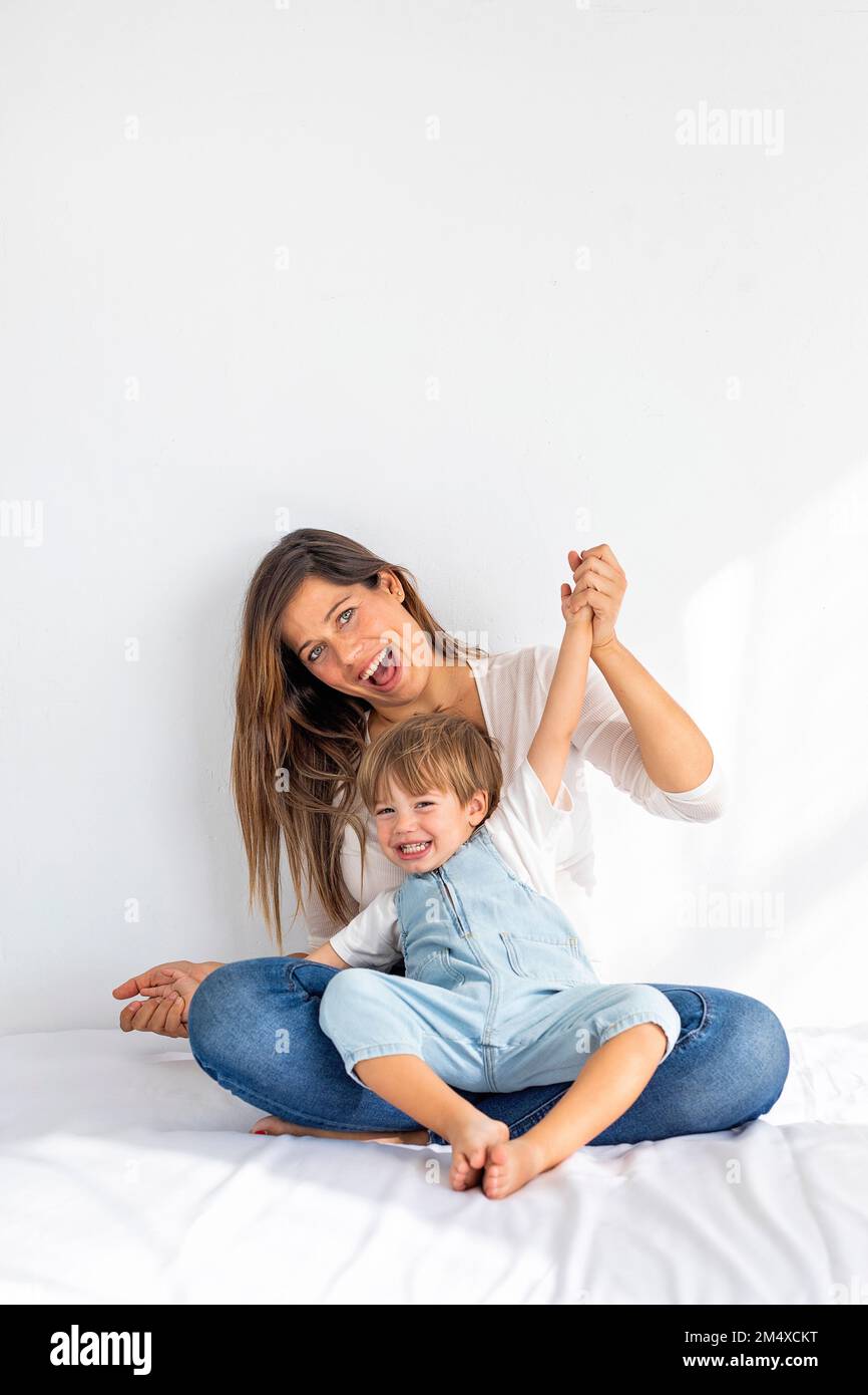 Happy woman and son having fun sitting on bed at home Stock Photo - Alamy