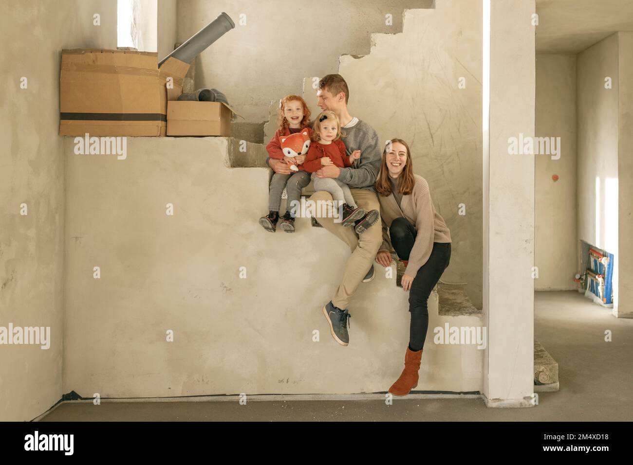 Happy family sitting on staircase at incomplete home Stock Photo - Alamy