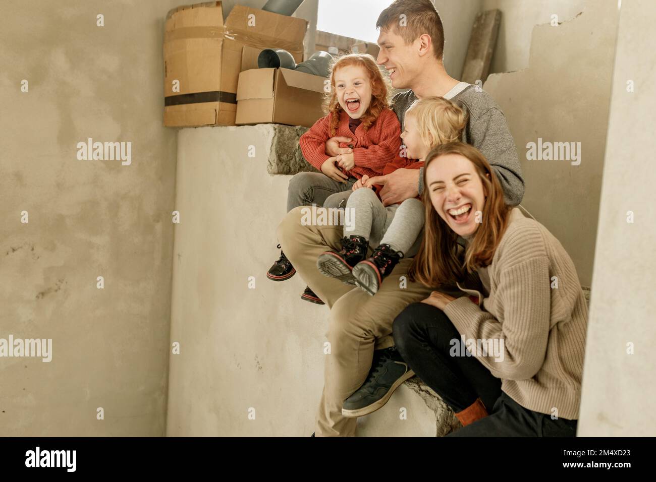 Happy family sitting on staircase enjoying at incomplete home Stock ...