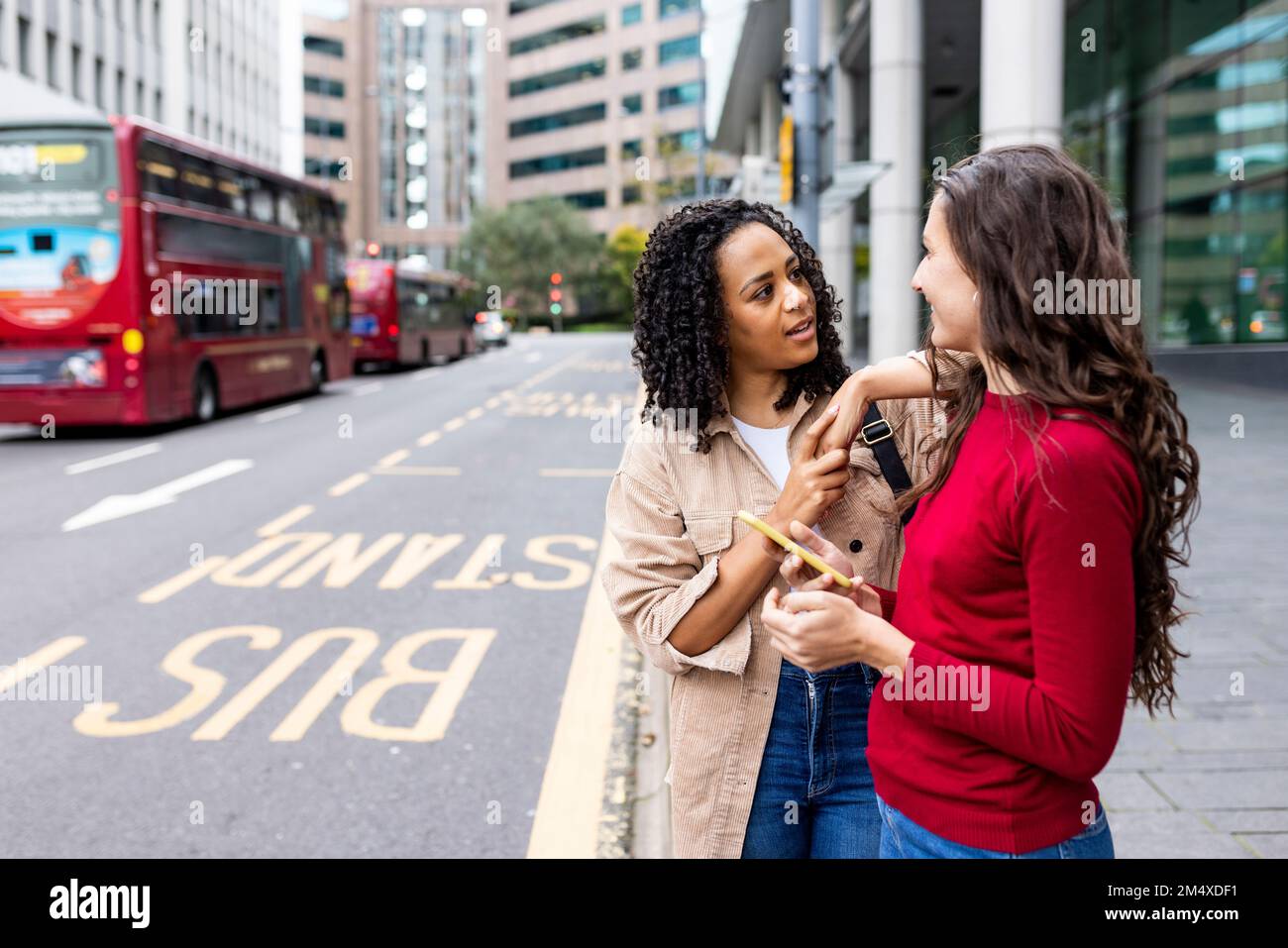 Woman having conversation with friend at bus stop Stock Photo - Alamy