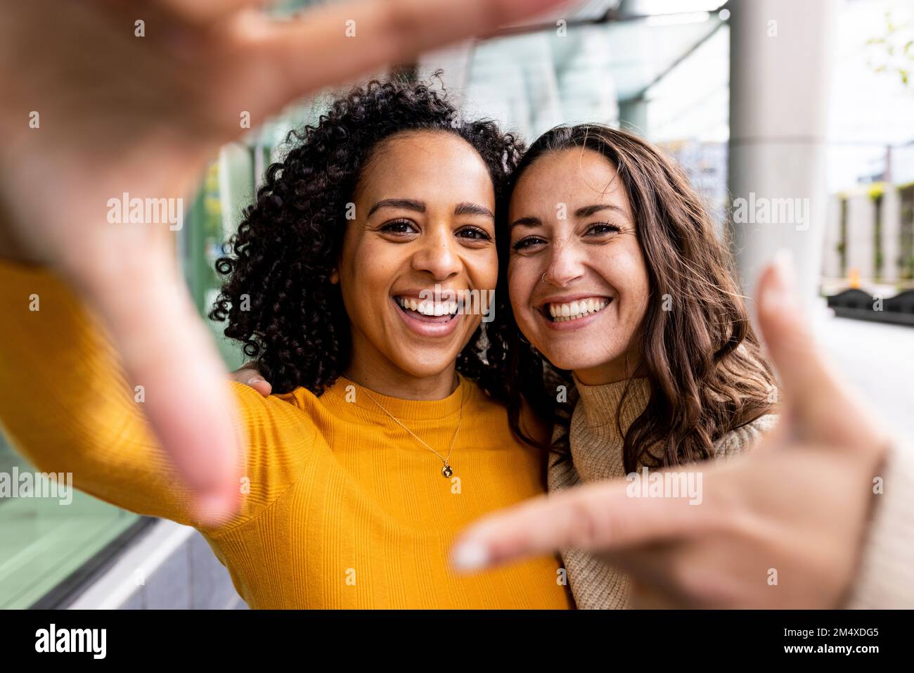 Cheerful friends making frame with fingers Stock Photo - Alamy